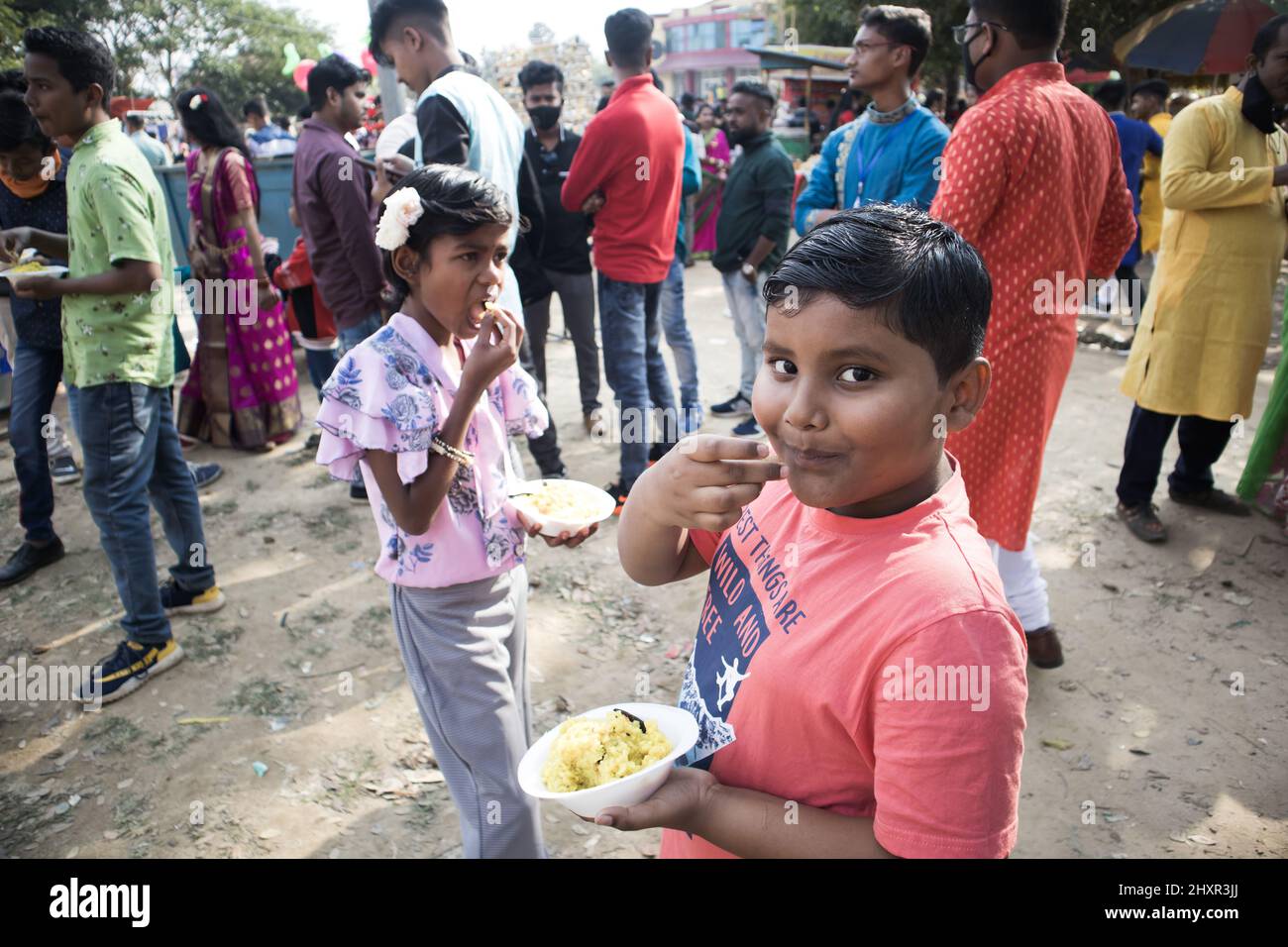 Tripura, India - February 5 2022: Kids taking khichdi prasad in a ... Tripura, India - February 5 2022: Kids taking khichdi prasad in a ...