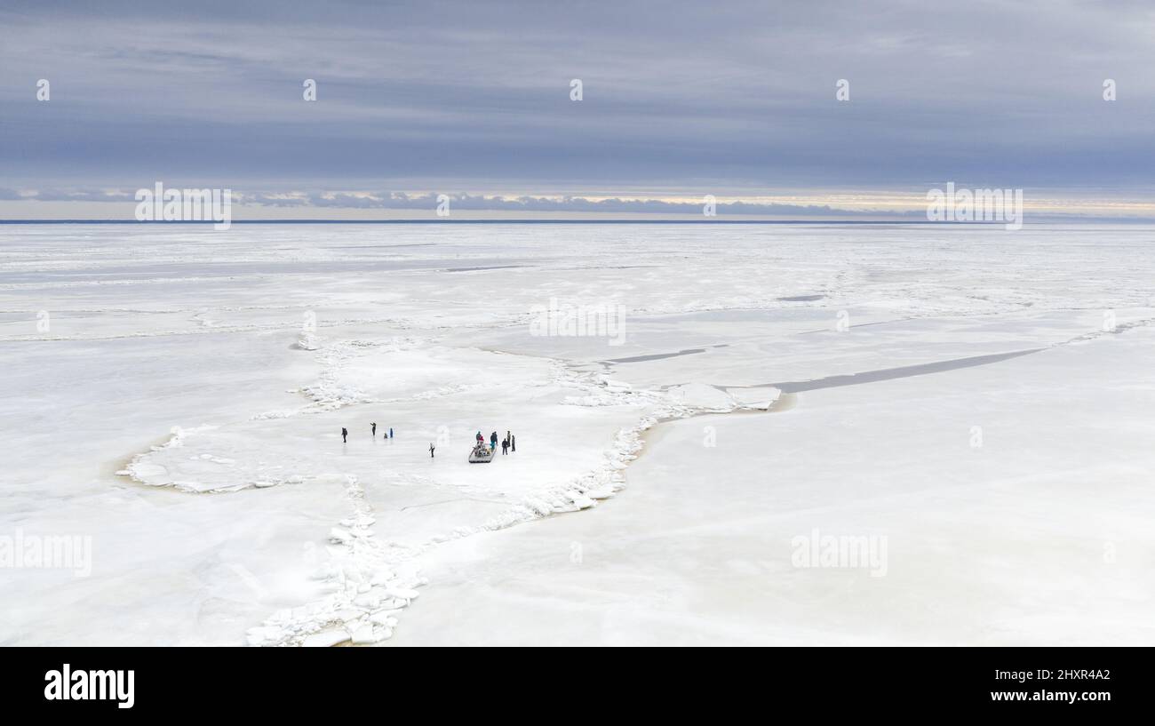 Group of distant people skating on the sea ice Stock Photo - Alamy