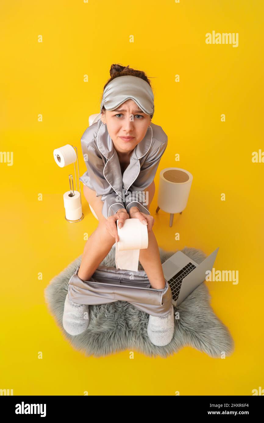 Young woman in pajamas suffering from diarrhea while sitting on toilet ...