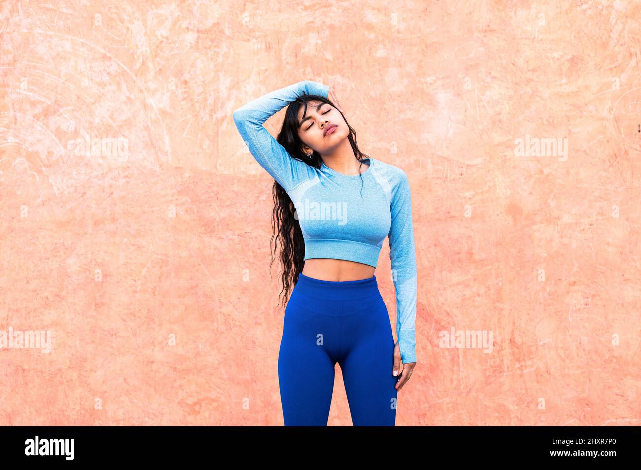 Attractive Colombian woman dressed in sportswear stretching her muscles ...
