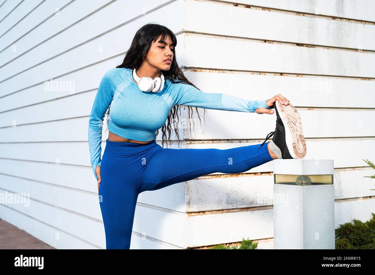 Attractive Colombian woman dressed in sportswear stretching her muscles ...