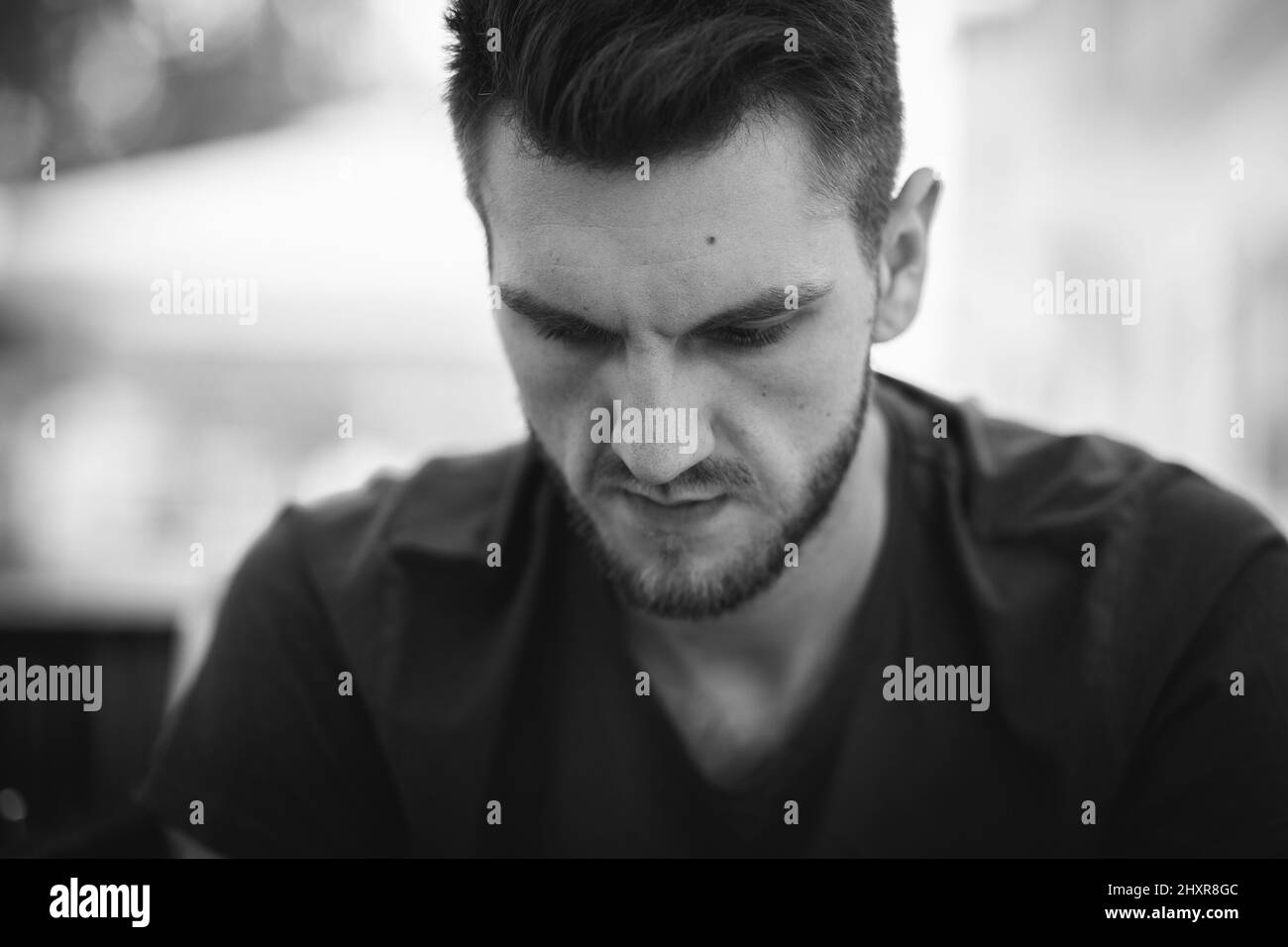 Closeup of a handsome male model looking down at something expressing ...