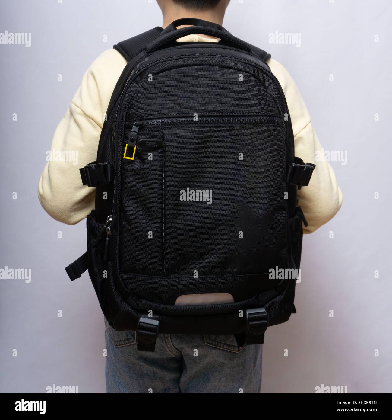 Asian child standing with a black backpack Stock Photo - Alamy