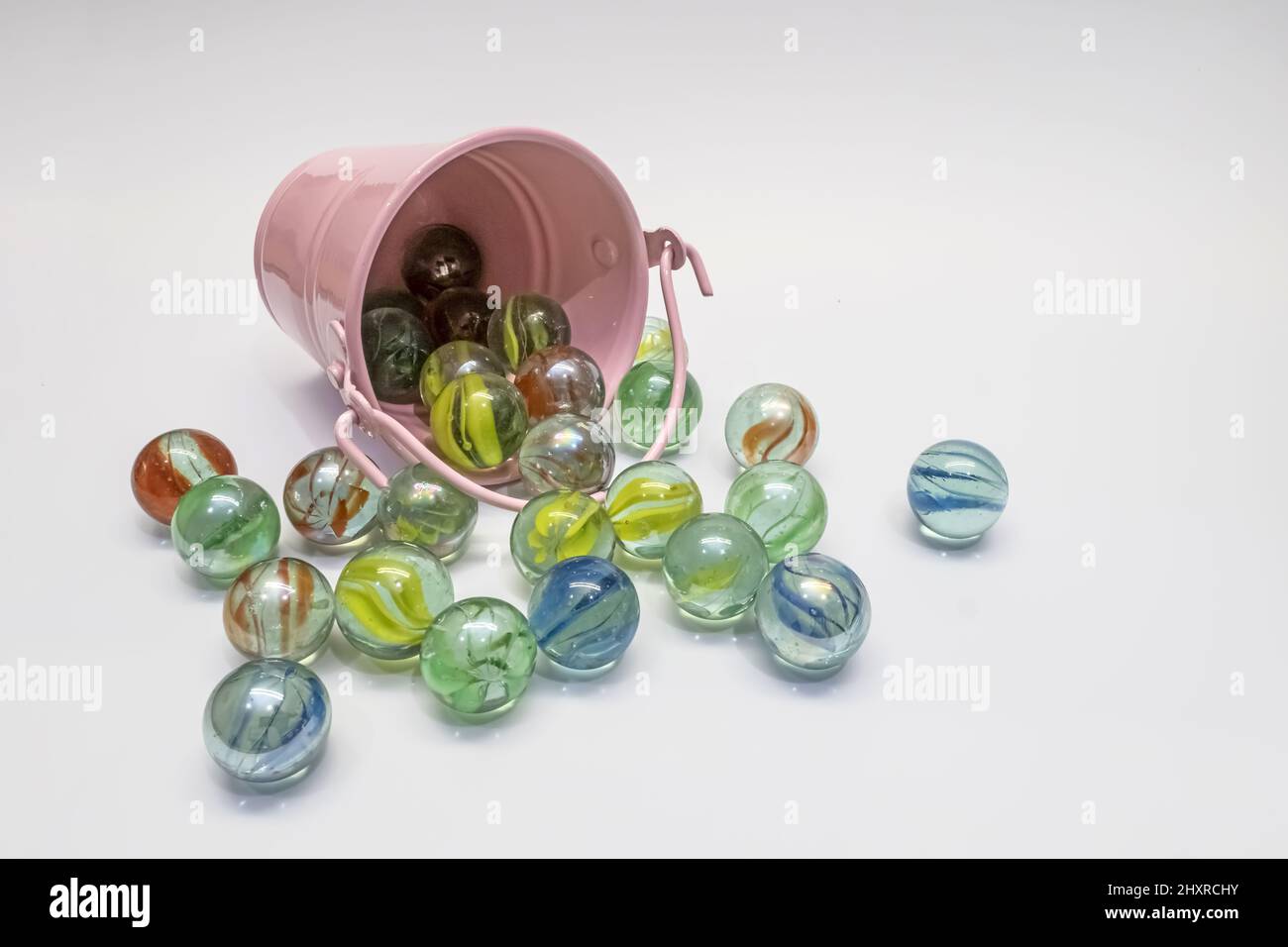 Closeup of colored glass marble balls in a small pink metal bucket on ...