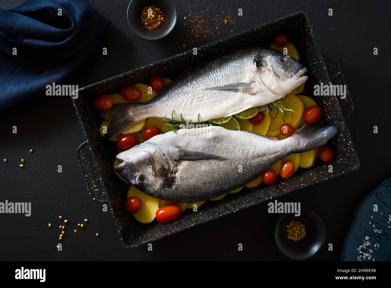 Fish in a baking sheet with potatoes and tomatoes, ready to bake Stock ...