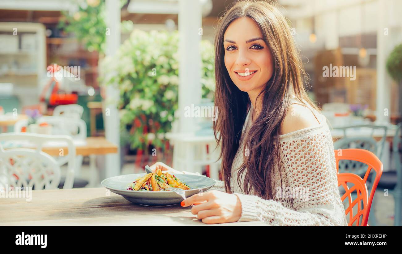 Young woman enjoying food in a restaurant, having her lunch break ...