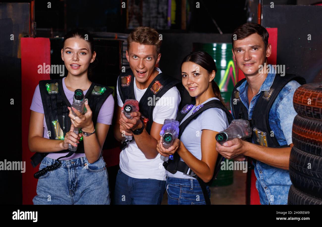 Group of friends playing laser tag game with laser guns in dark ...