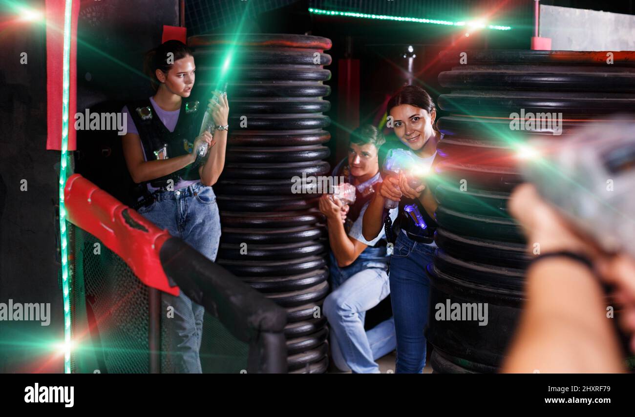 friends playing laser tag game with laser guns near tires Stock Photo ...