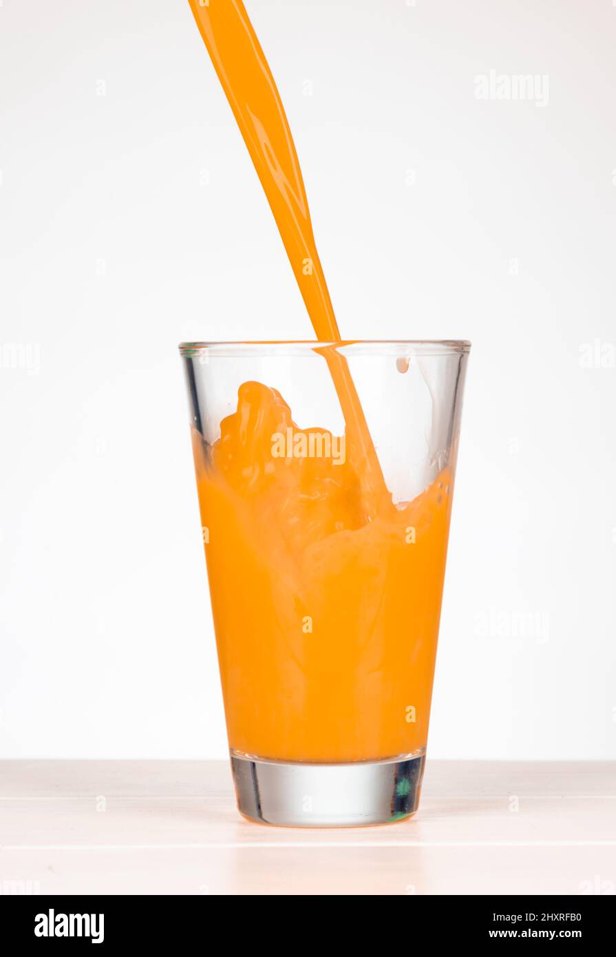 Multivitamin juice pouring in a glass Stock Photo - Alamy