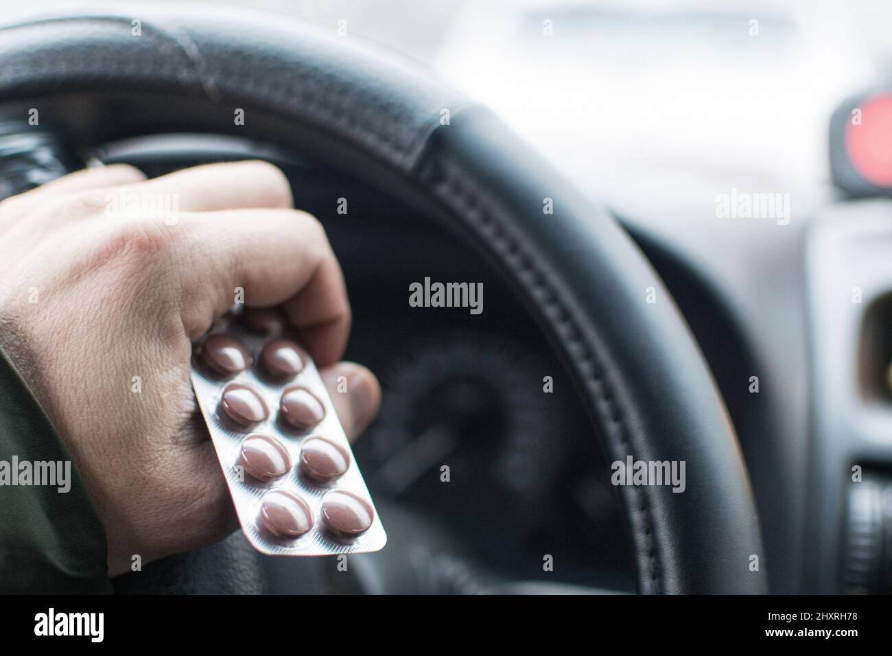 Medical pills and car driving. Male hand holds blister with pills on ...