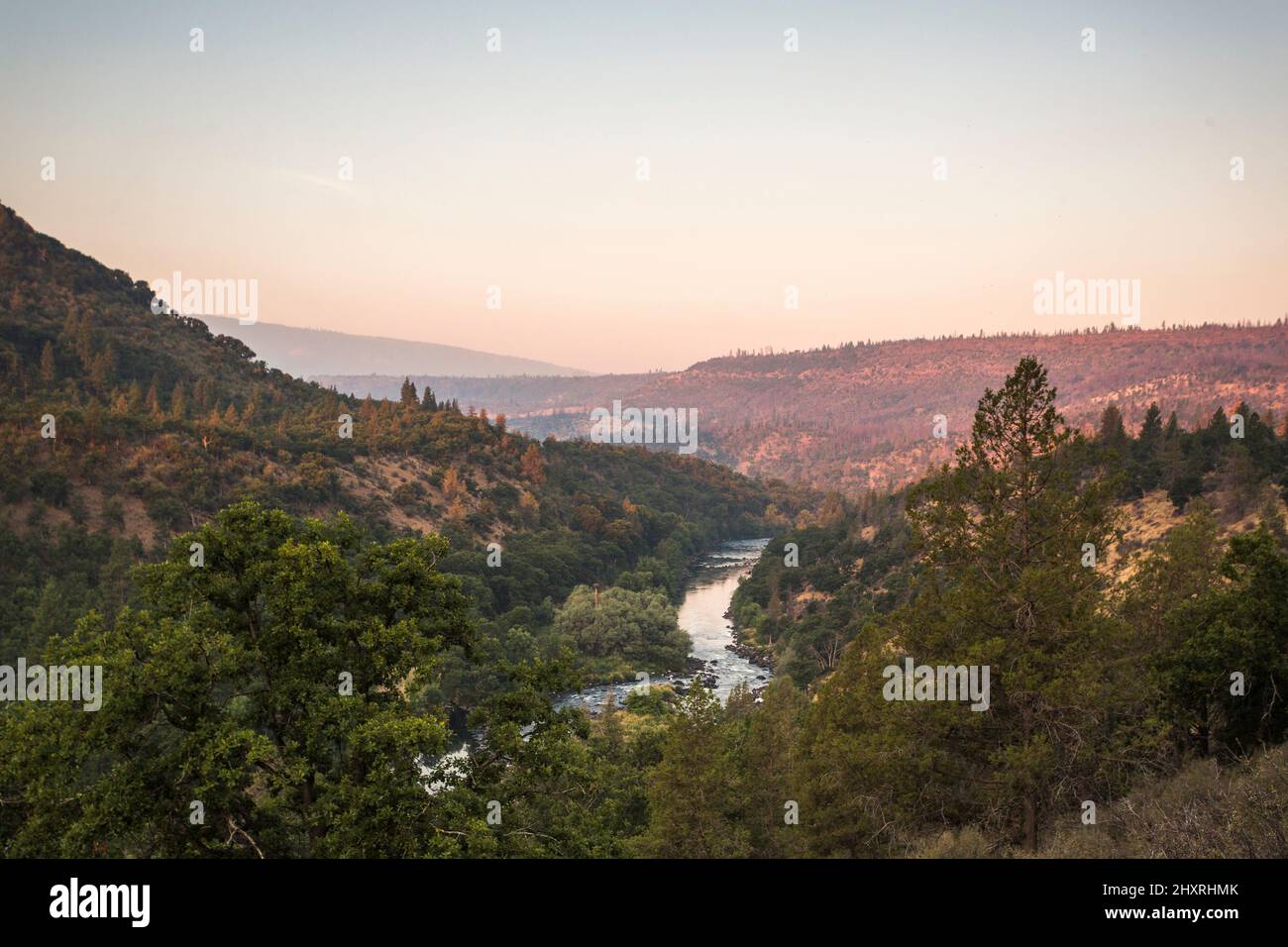 A river flows through forested hills at sunset Stock Photo - Alamy