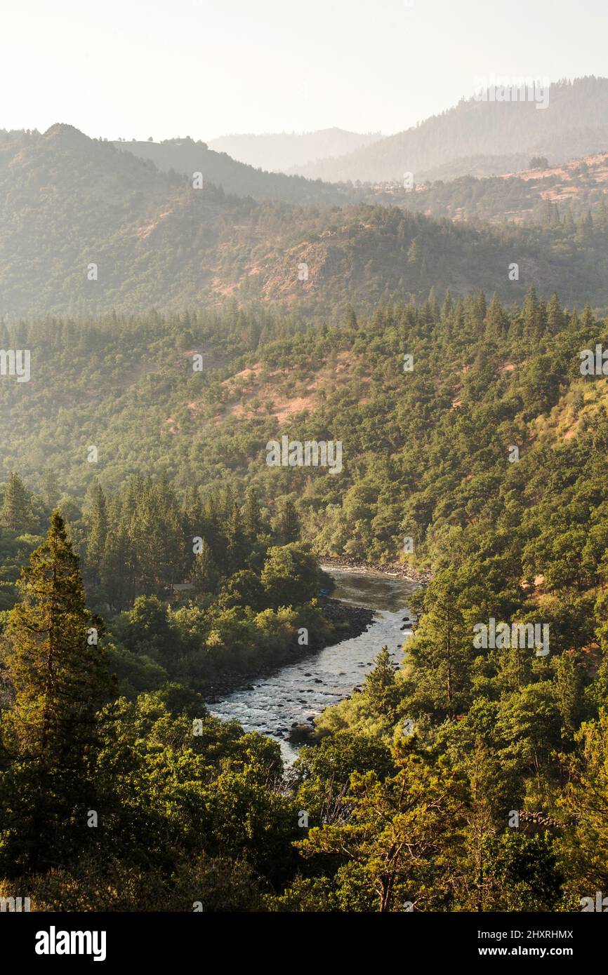 A river flows through forested hills at sunset Stock Photo - Alamy