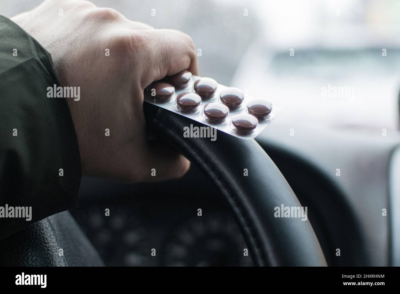 Medical pills and car driving. Male hand holds blister with pills on ...