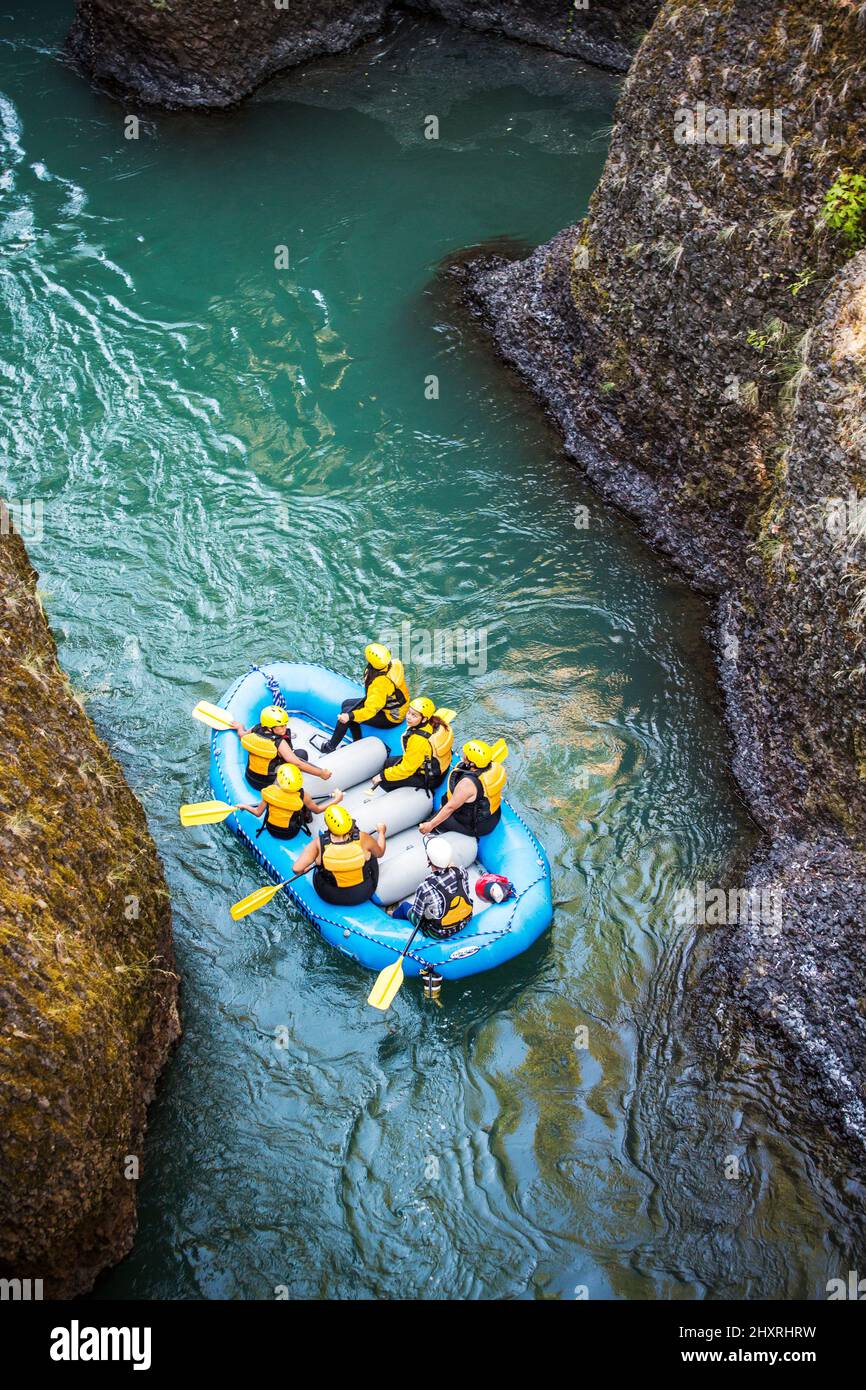 A raft with kids paddles through a deep river canyon Stock Photo - Alamy