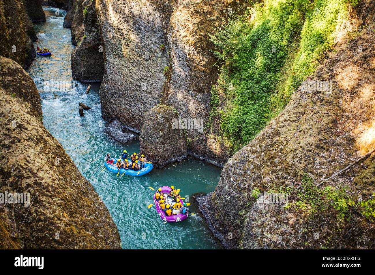 Three rafts with kids paddles through a deep river canyon Stock Photo ...