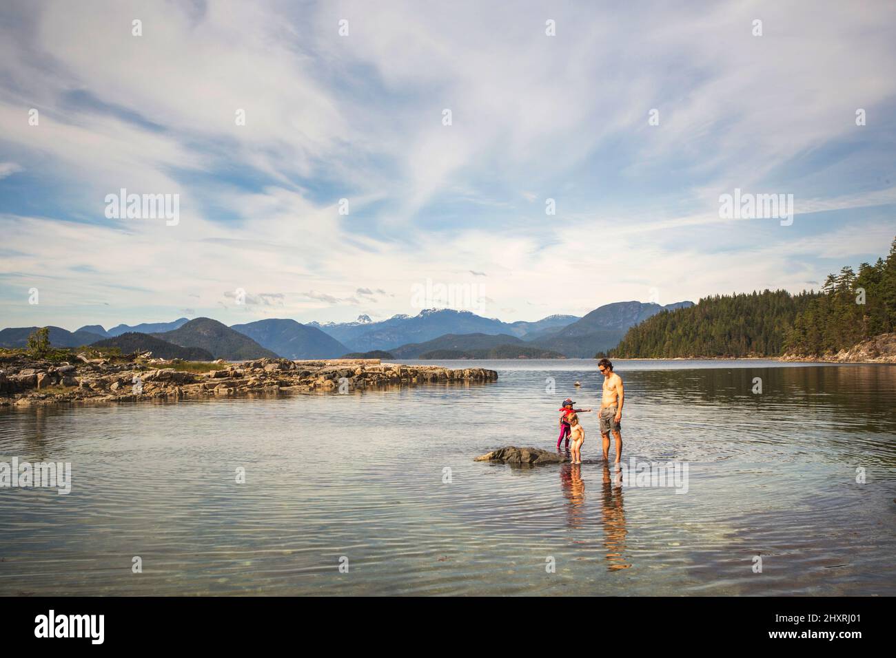 A man stands in shallow water with two young kids in big bay Stock ...