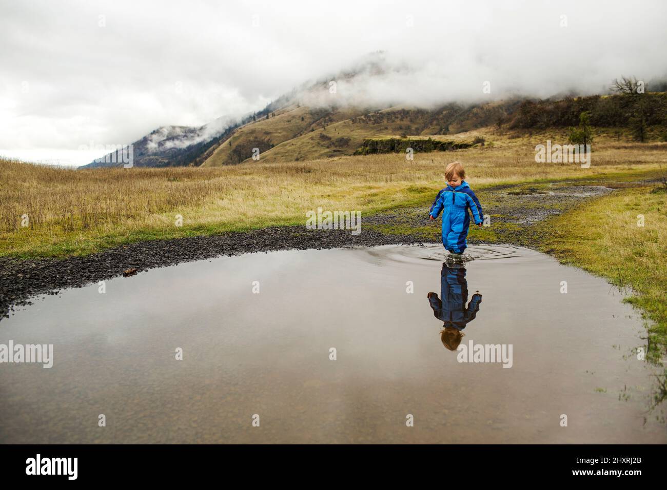 A young child walks through a shallow puddle in a wide landscape Stock ...