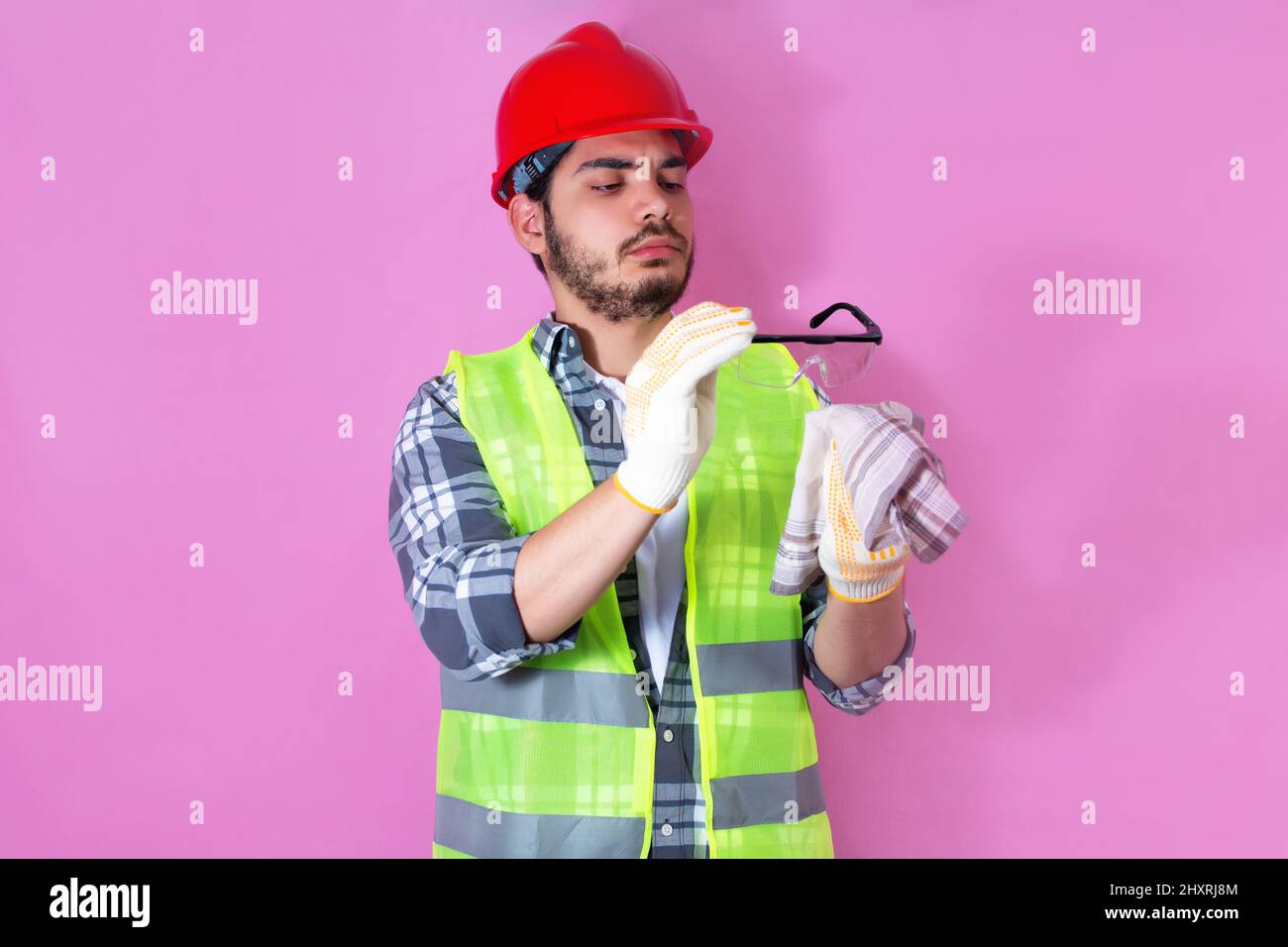 Worker cleaning safety goggles isolated on pink background Stock Photo ...