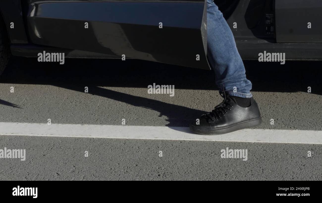 Man getting into car on drivers side. HDR. Close up of male legs in ...
