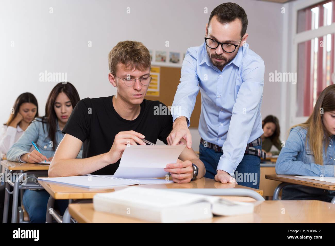 Student is writing test and answer about task and teacher is explaining ...