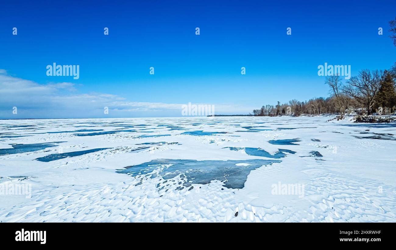 The lake is scattered with snow along the shoreline with a clear sky ...
