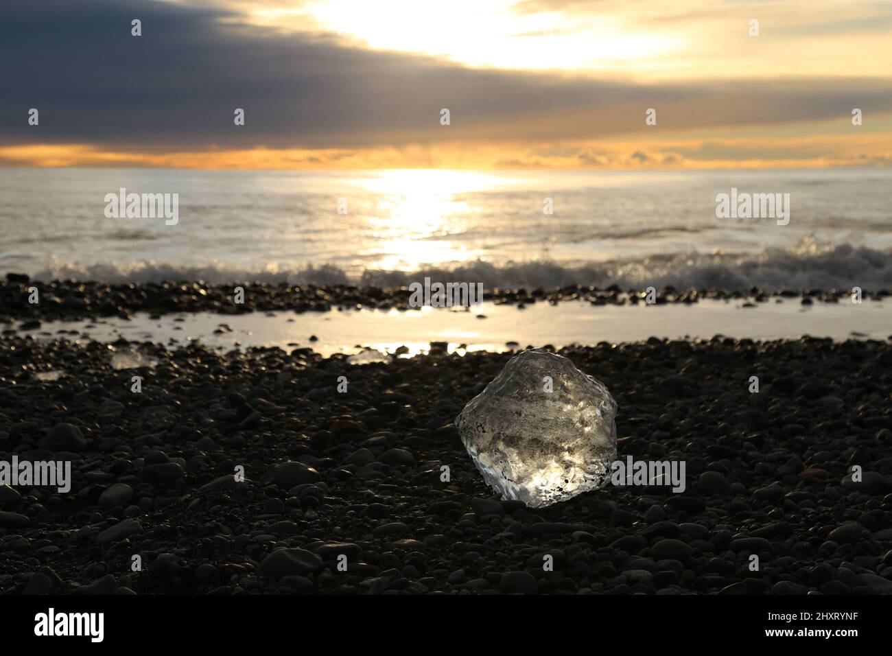 Beautiful view of a big ice colt on the stone beach by the shiny water ...