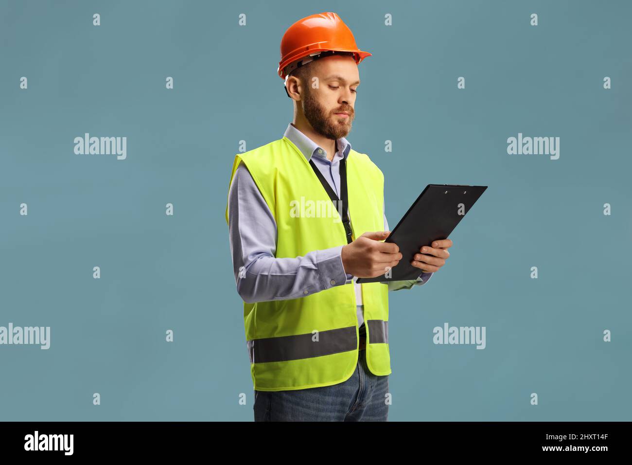 Male engineer wearing a reflective vest and helmet holding a clipboard ...