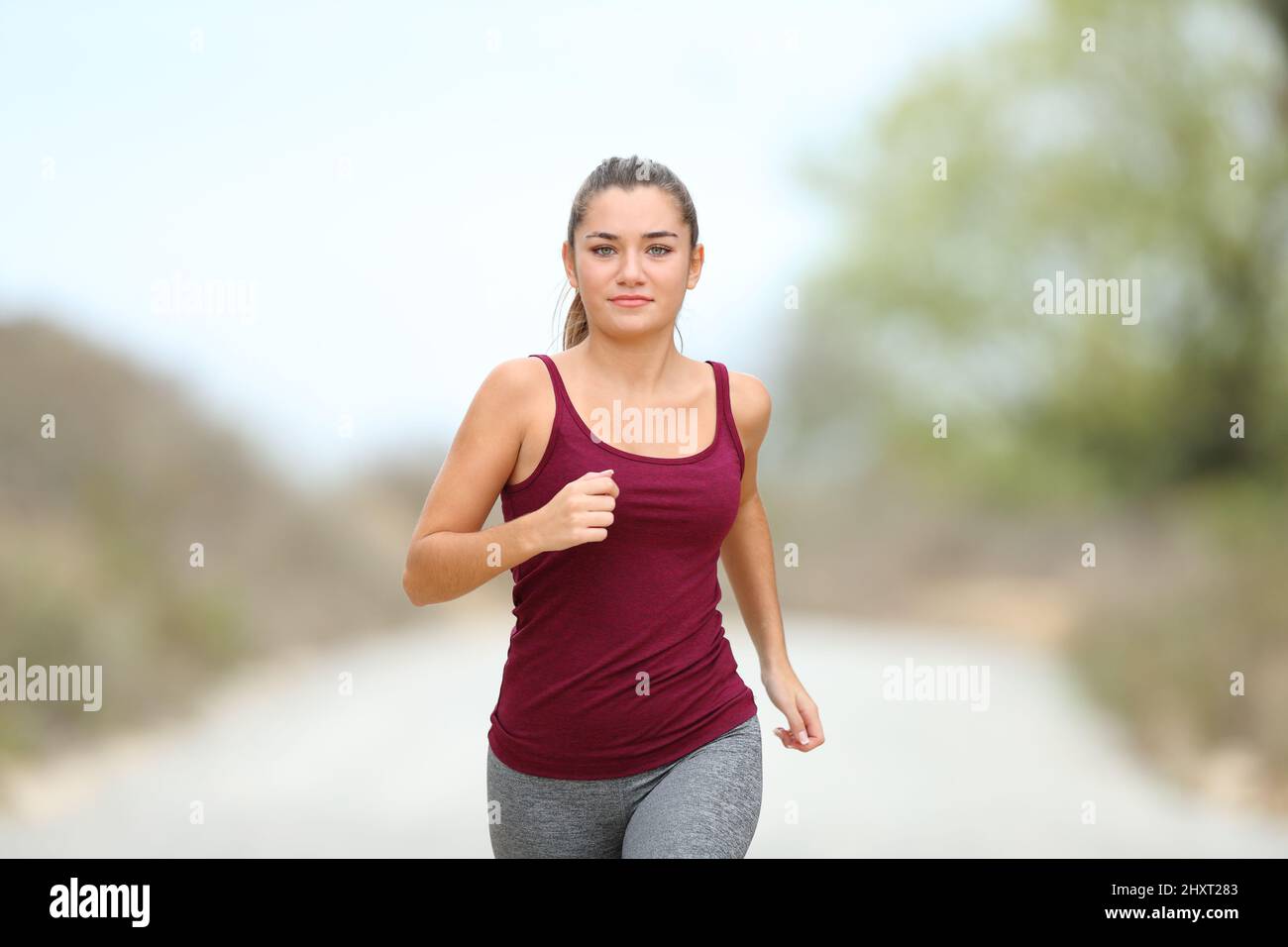 Front view portrait of a runner jogging towards camera in the mountain ...