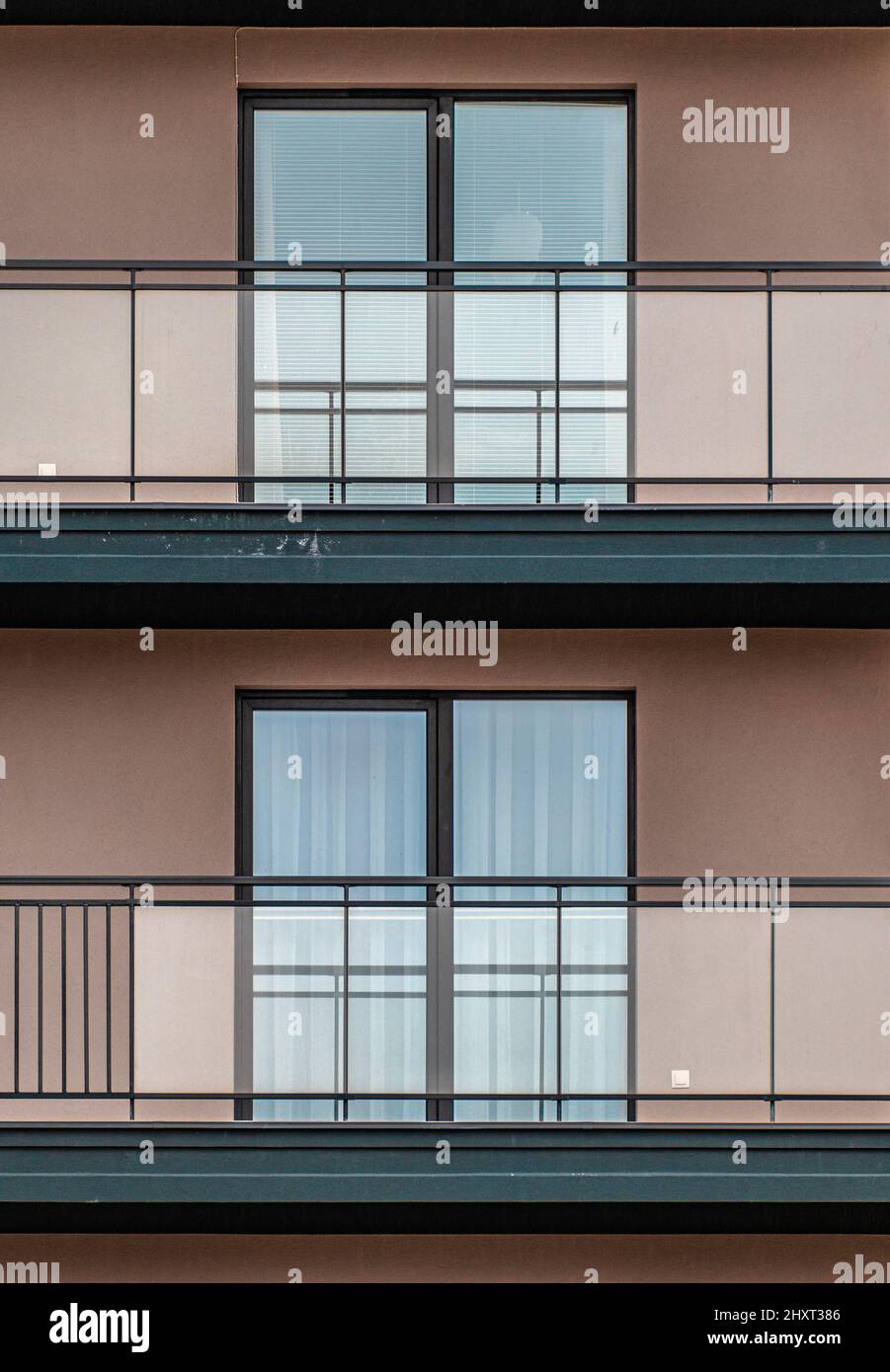 Vertical symmetric shot of two balconies and windows with pink walls ...