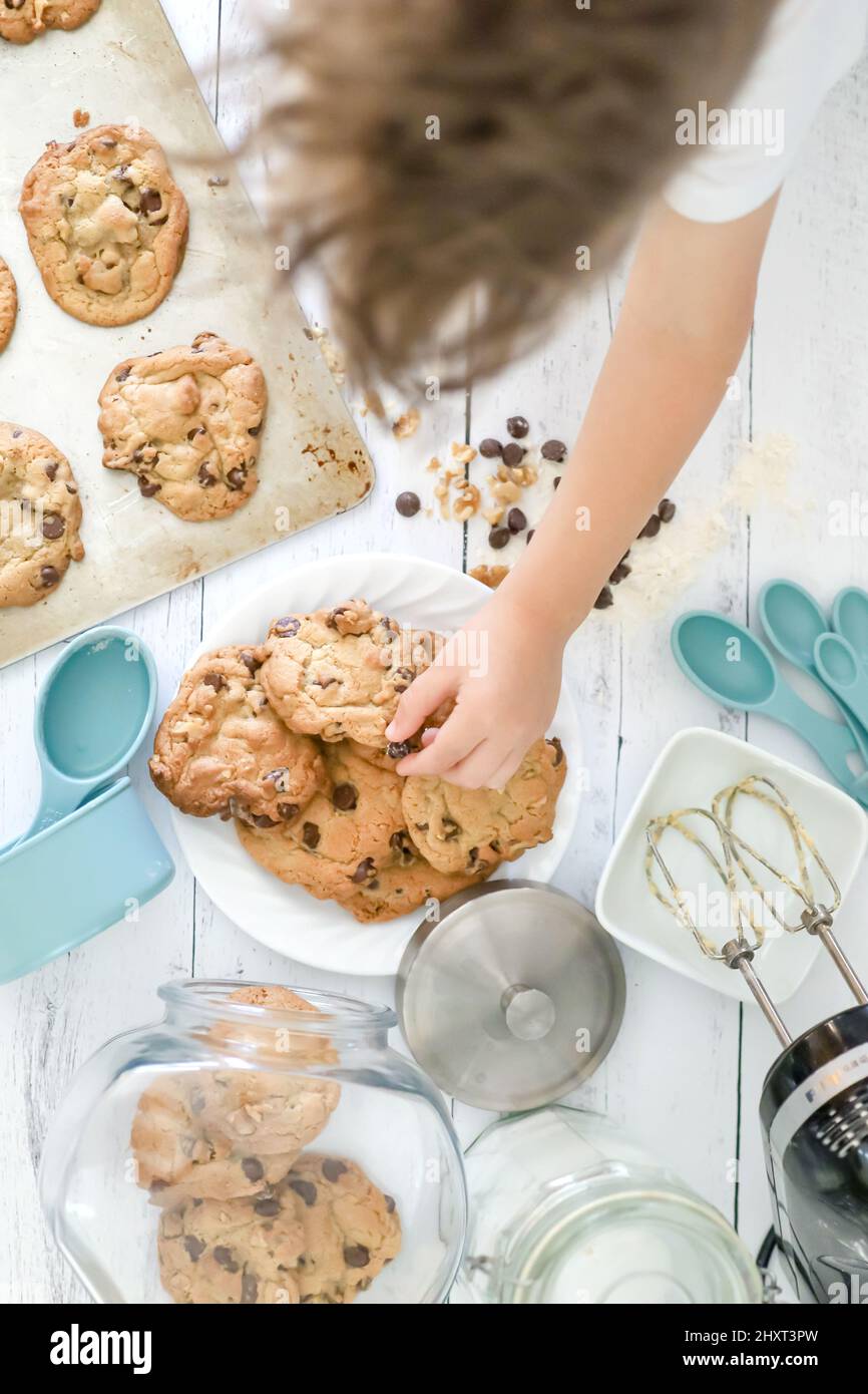 Vertical top view of a child reaching for a freshly baked cookie on a ...