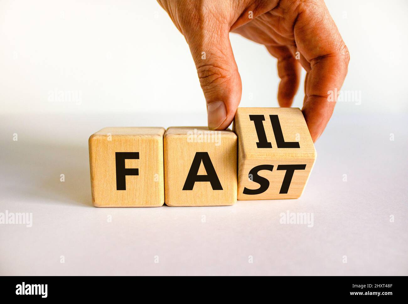 Fail fast symbol. Businessman turns the wooden cube with concept words ...