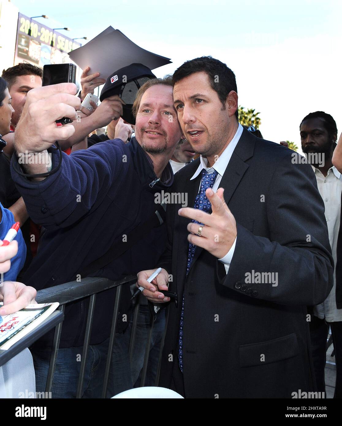 Adam Sandler signing autographs for fans at a ceremony where he was ...