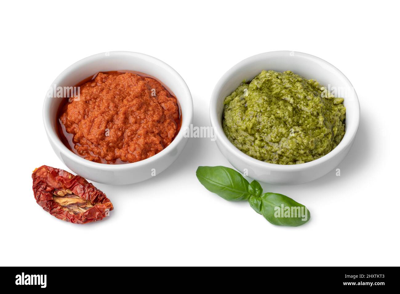 White bowls with red and green Italian pesto close up isolated on white ...