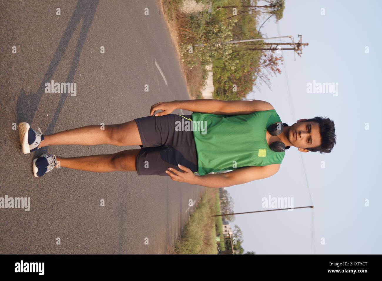 Vertical closeup of the young man in a sports outfit training outside ...