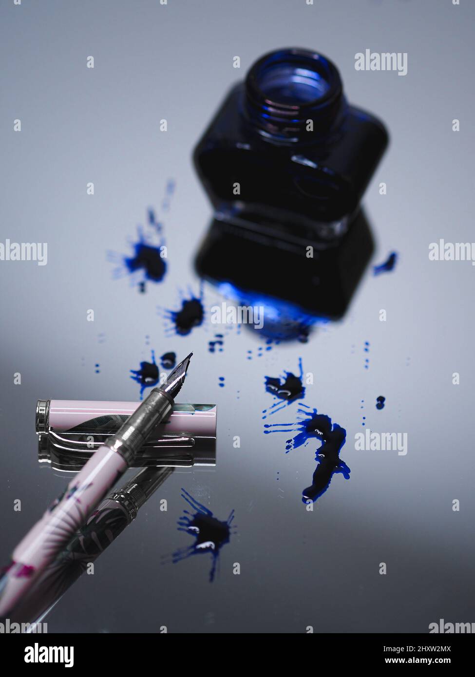 Vertical selective focus shot of an ink bottle on a mirror table and ...