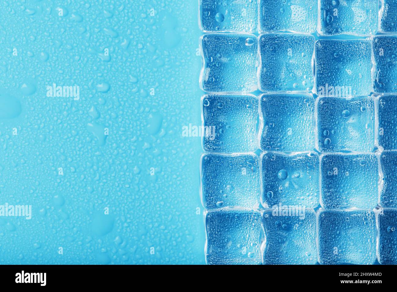 Many frosty and refreshing ice cubes with drops on a blue background ...