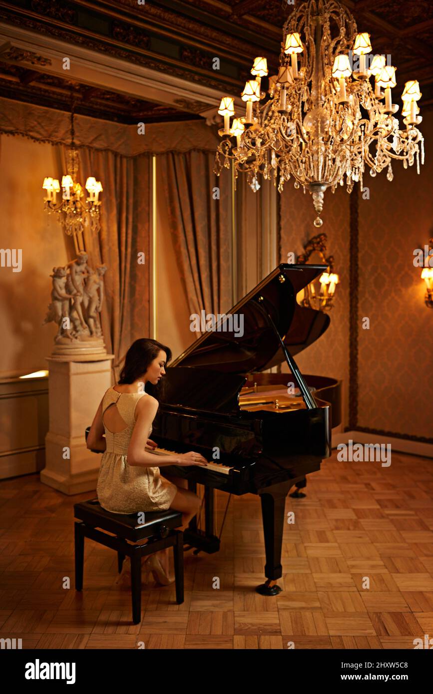 Classic perfection. Shot of a beautiful young woman playing the piano ...