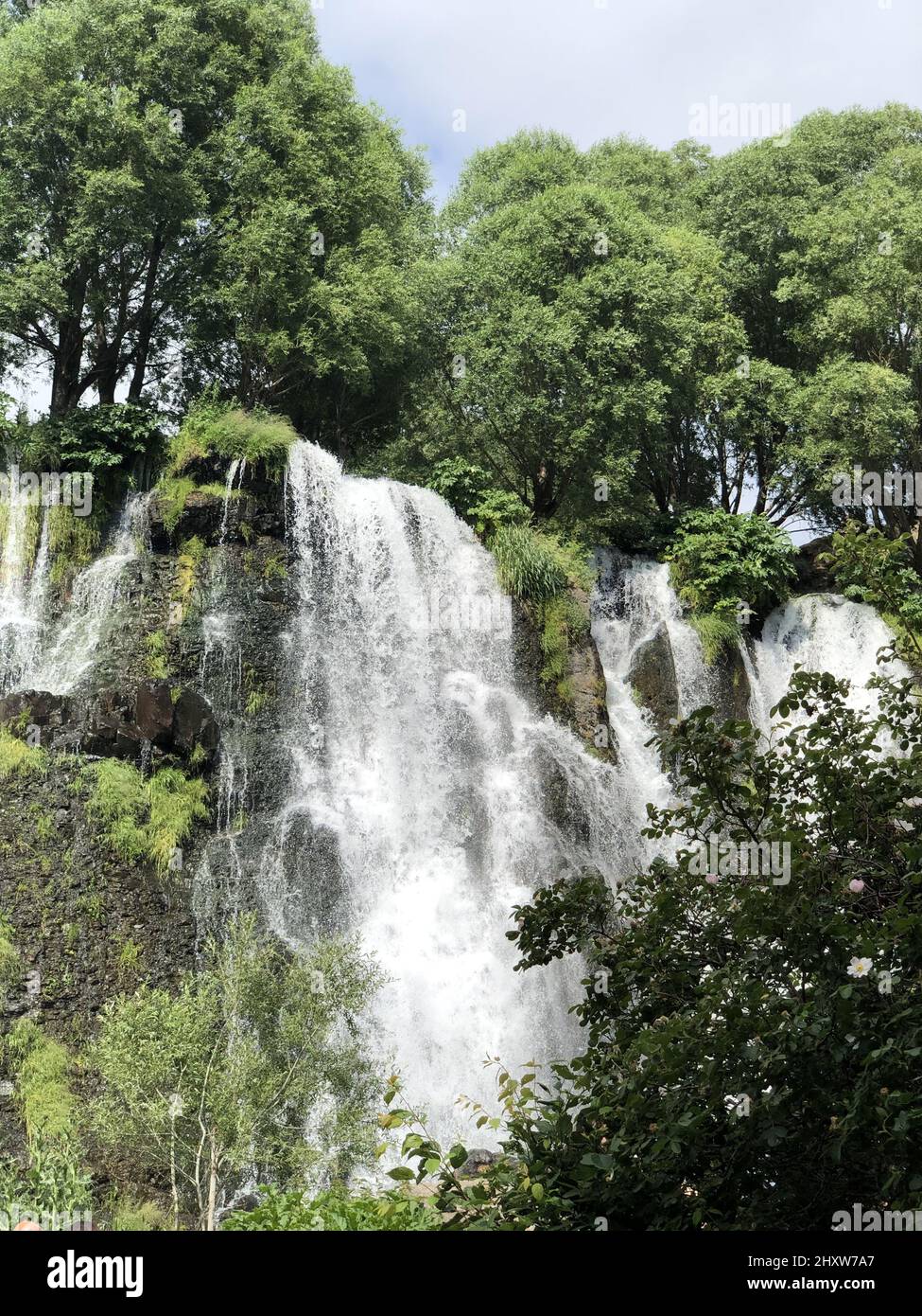 Vertical shot of the beautiful Shaki waterfall surrounded by greenery ...
