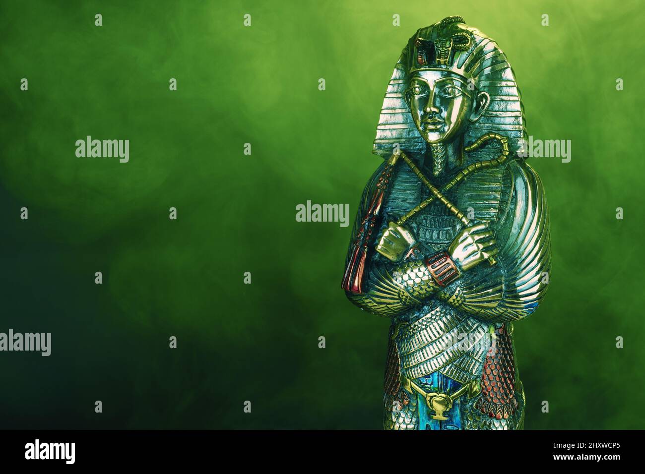 Egyptian pharaoh figurine in green smoke on a black background. side ...
