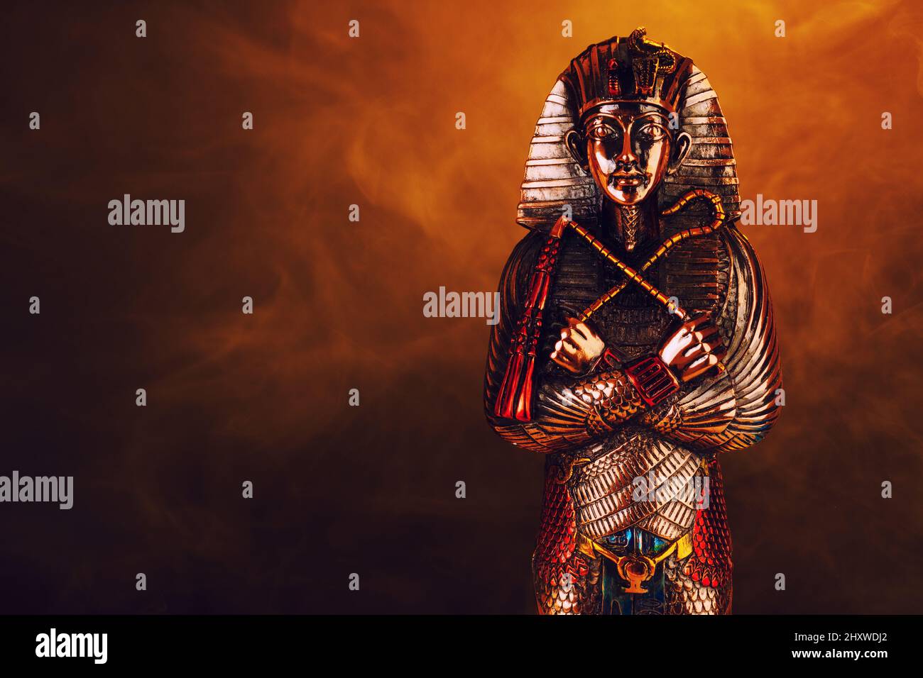 Egyptian pharaoh figurine in orange smoke on a black background. High ...