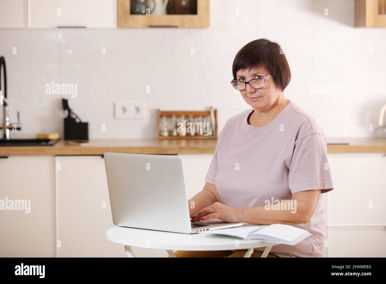 mature old lady working remotely from home office on laptop making ...