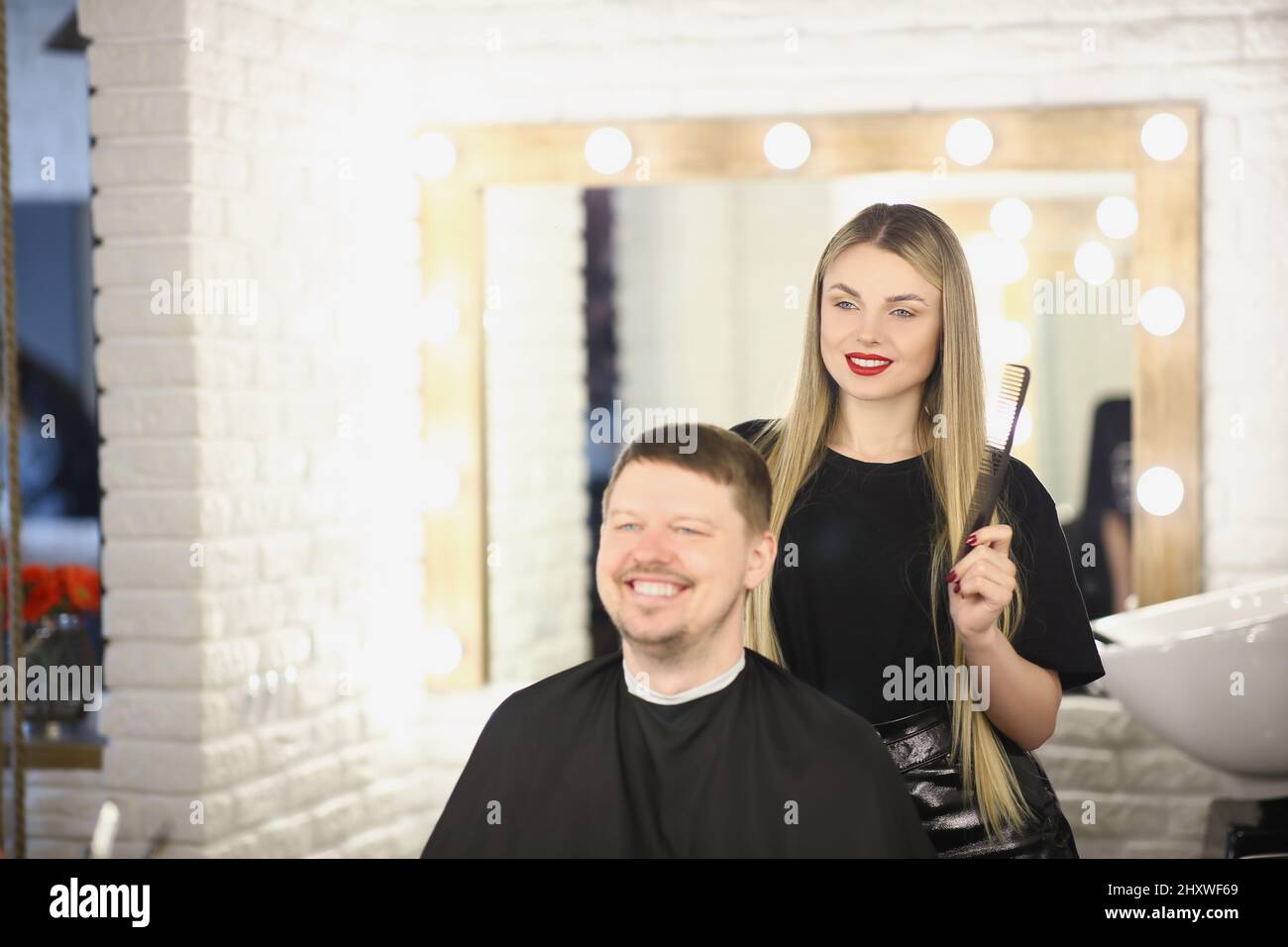 Pretty professional female master holding brush for modeling hairstyle ...