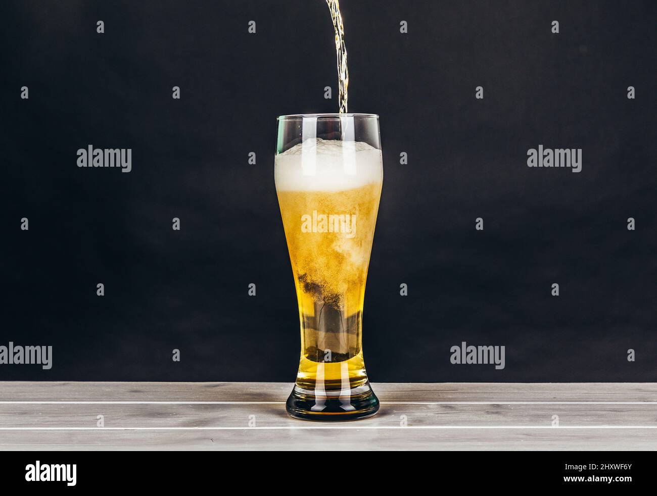 Beer glass being filled against a black background Stock Photo - Alamy