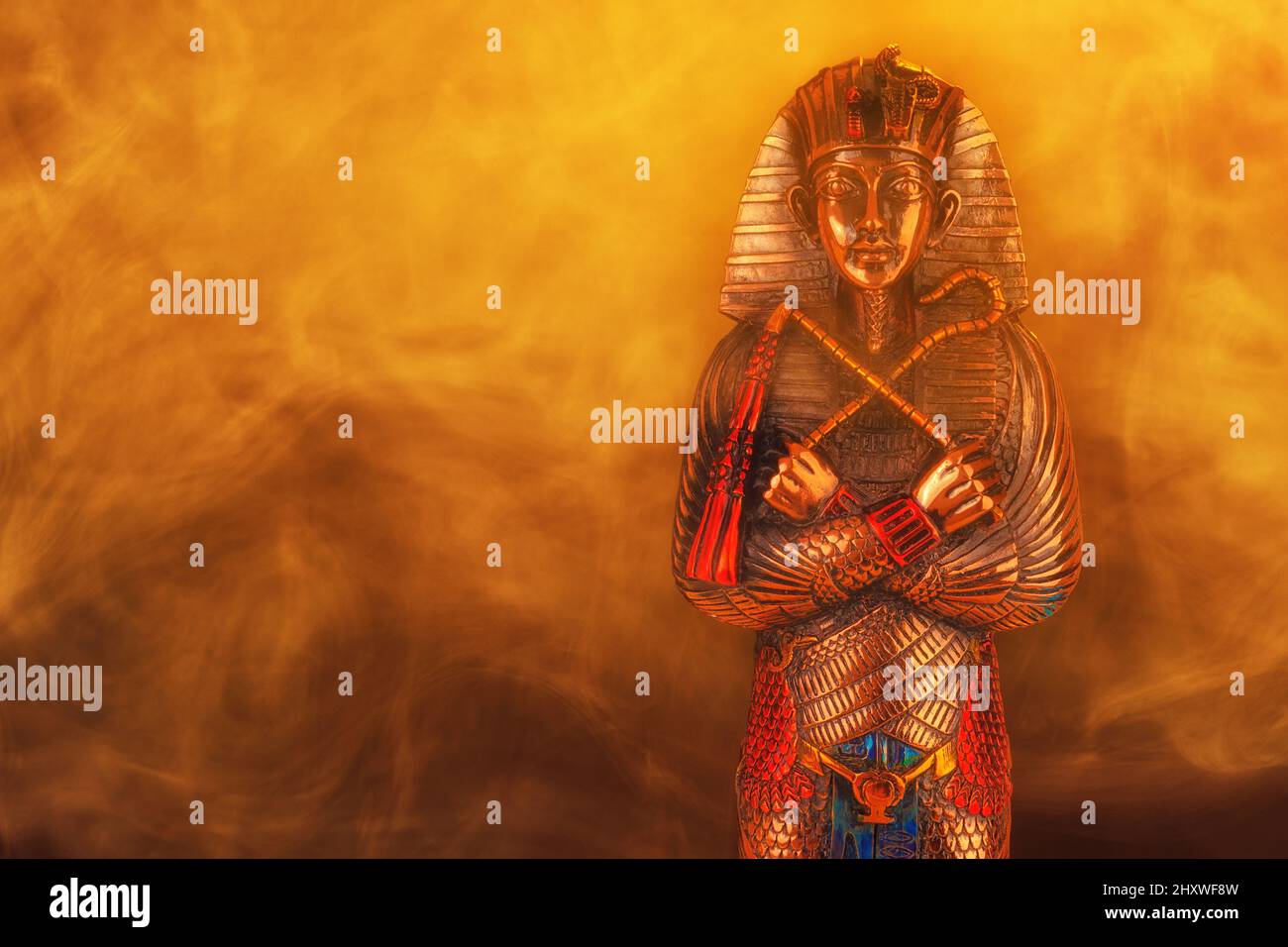 Egyptian pharaoh figurine in yellow smoke on a black background. side ...