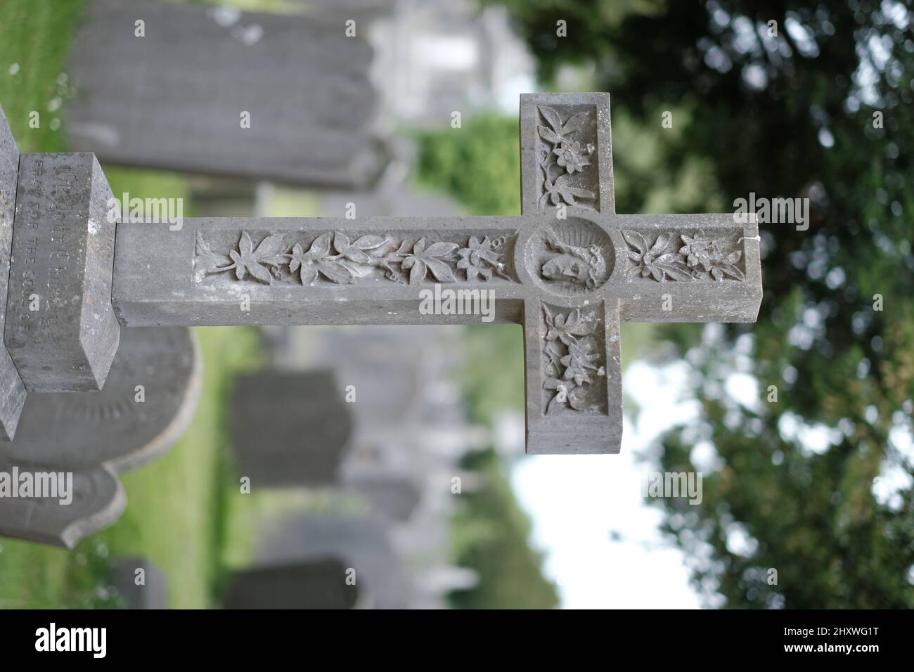 Vertical shallow focus of a large carved stone cross with a background ...