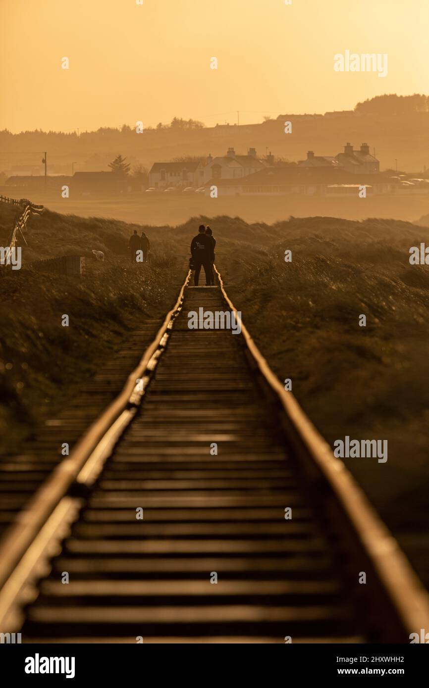 Couple walks down the rail track in a golden hour Stock Photo - Alamy