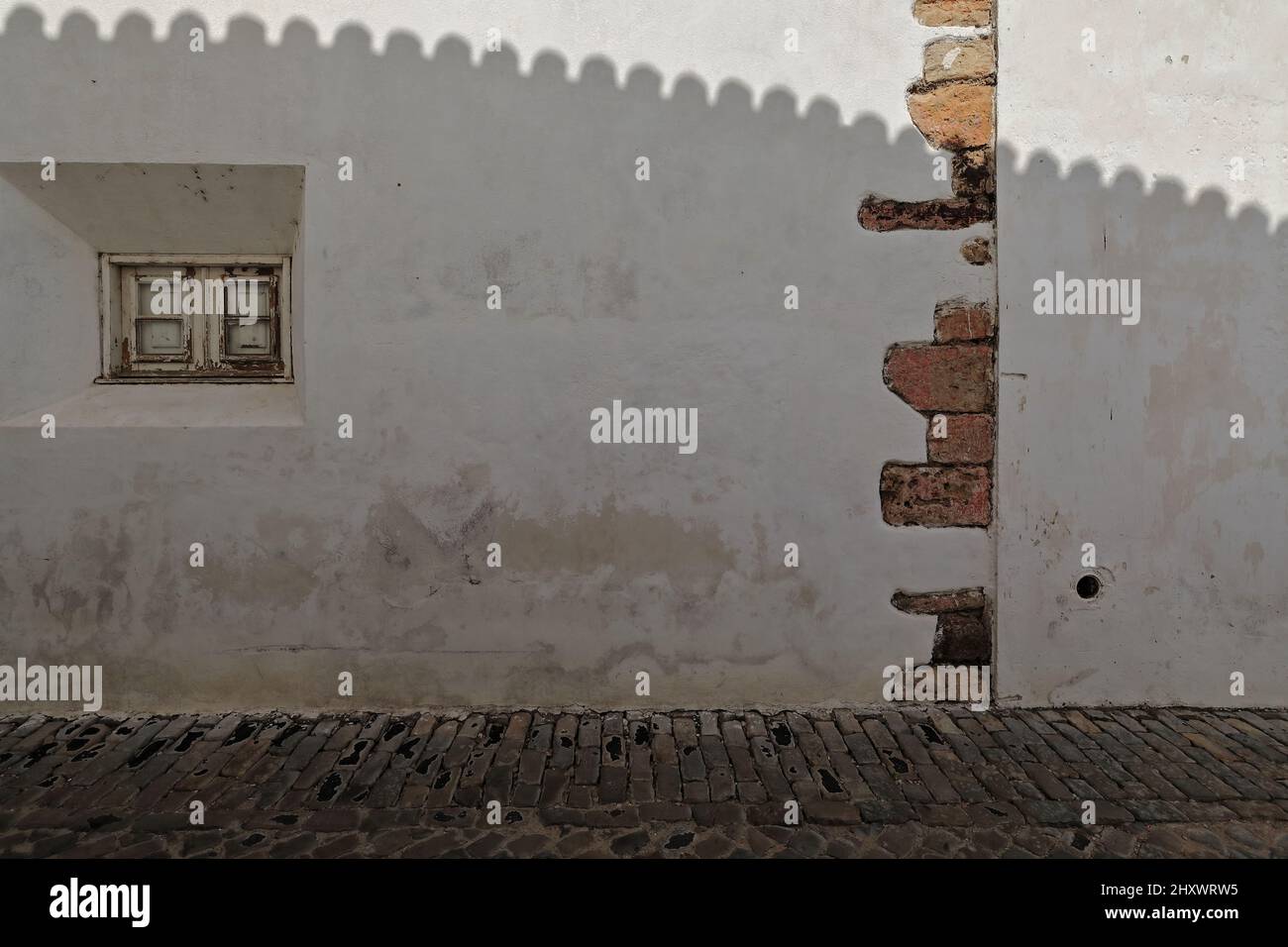 Small recessed window-peeling paint casing-roof shadow cast-whitewashed ...