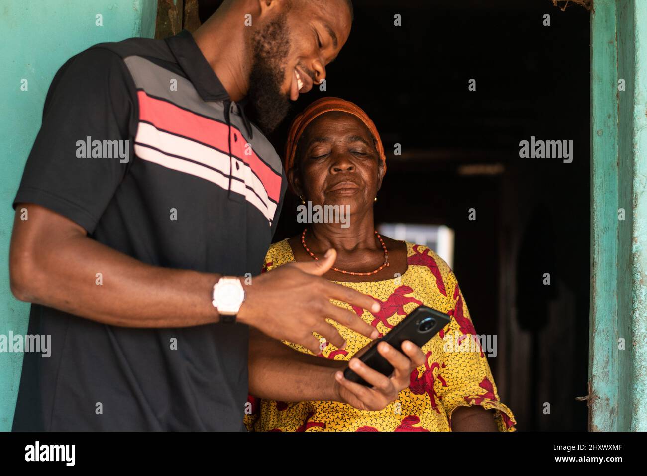 Young African man explaining to an elderly african woman how to use the ...