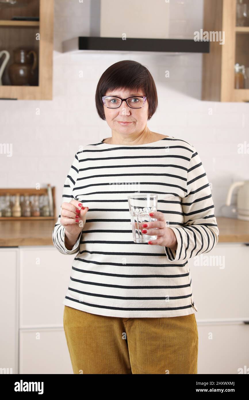 Smiling happy healthy senior woman at home holding glass of natural ...
