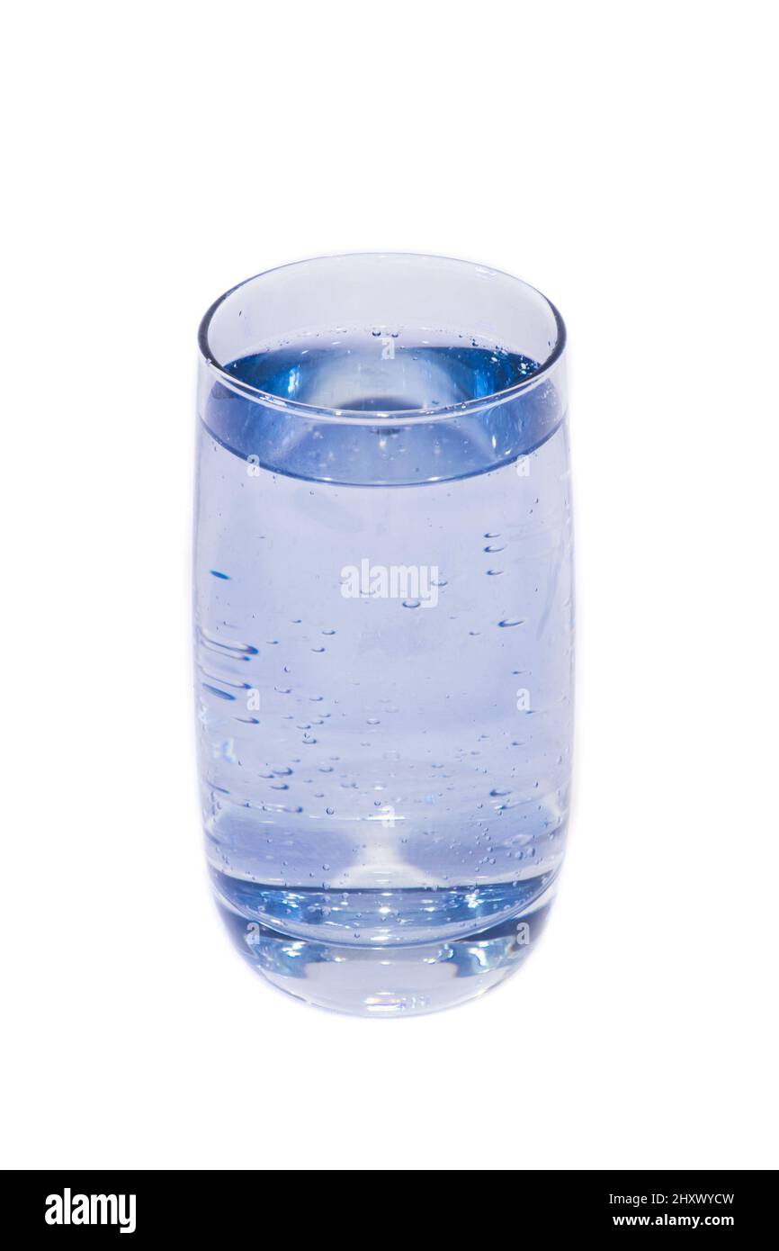 The glass filled of pure mineral sparkling water isolated on white background. Blue tone Stock ...